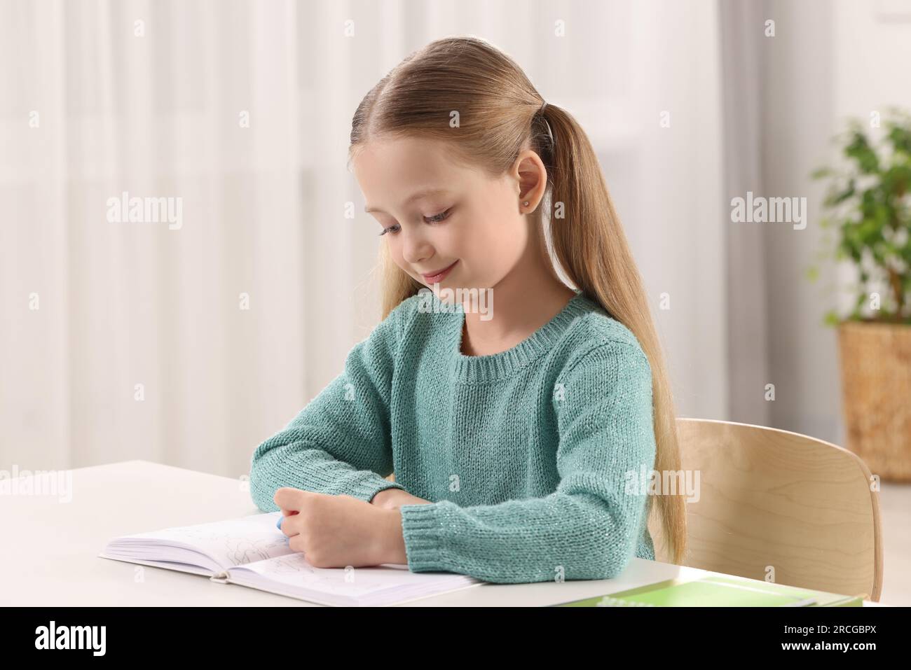 Girl using eraser at white desk in room Stock Photo - Alamy