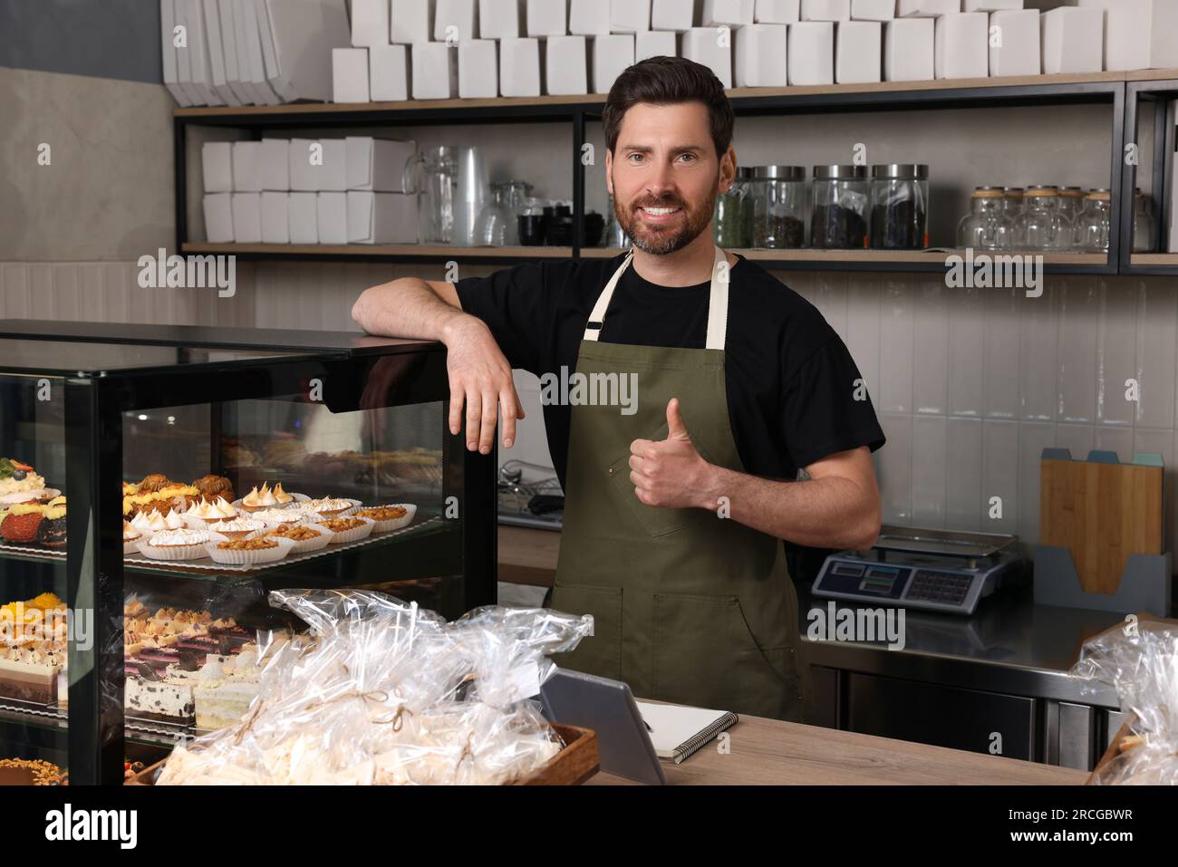 Happy seller showing thumb up at cashier desk in bakery shop Stock ...