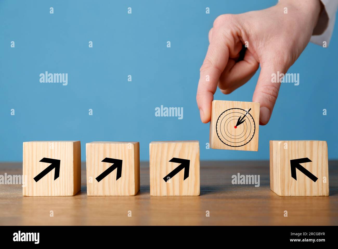Woman putting cube with icon of target into row of cubes with arrows ...