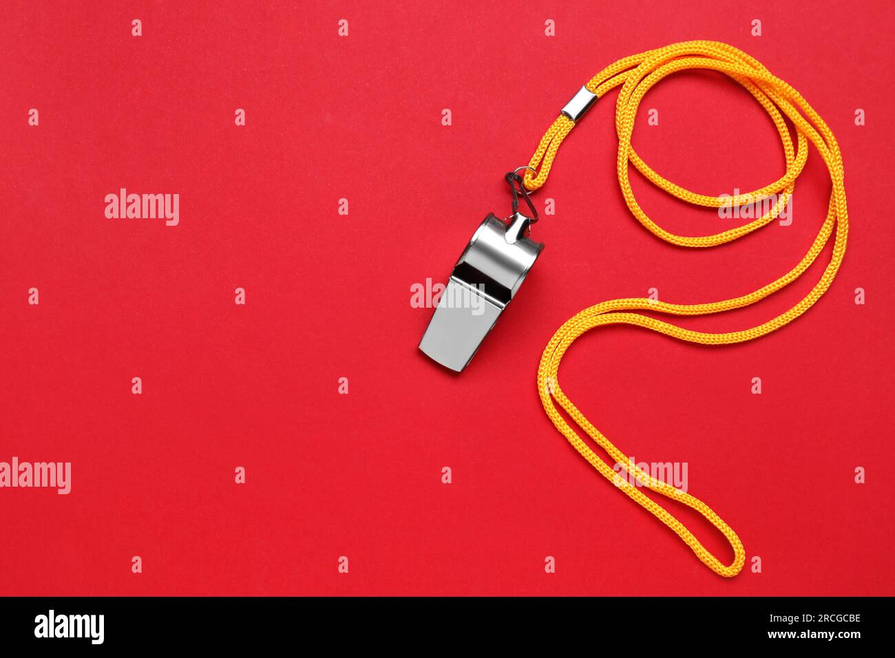 One metal whistle with cord on red background, top view. Space for text ...