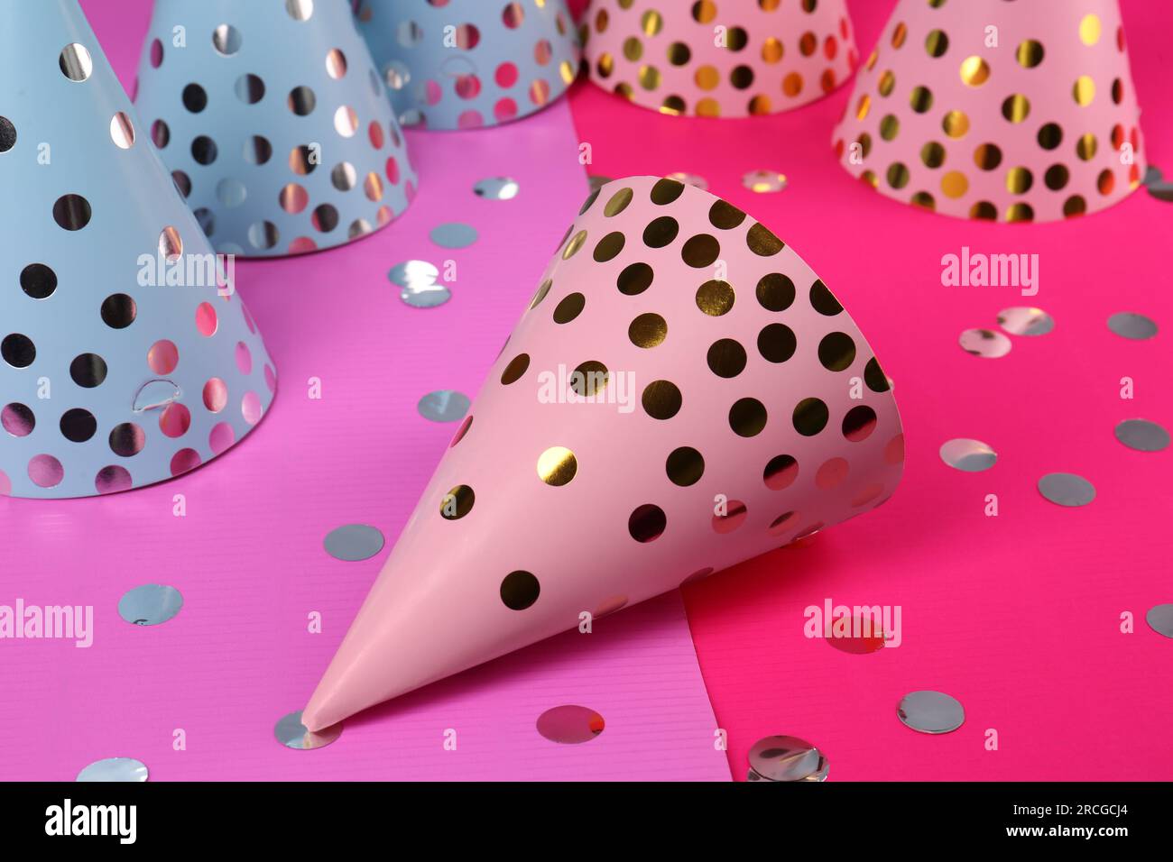 Bright party hats with confetti on color background. Handmade ...