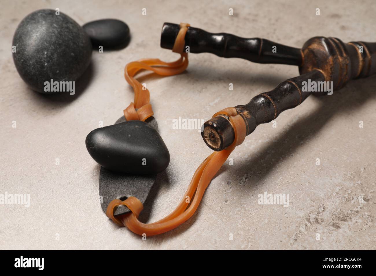 Black slingshot with stones on light grey table, closeup Stock Photo ...