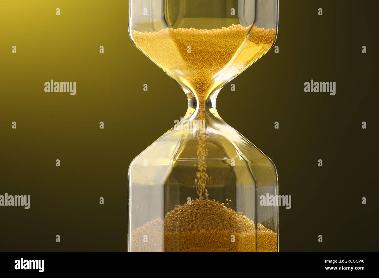 Hourglass with golden flowing sand on color background, closeup Stock ...
