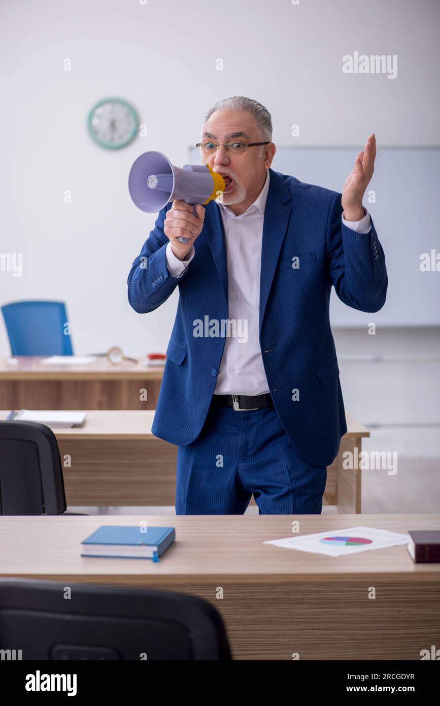 Old teacher holding megaphone in the classroom Stock Photo - Alamy