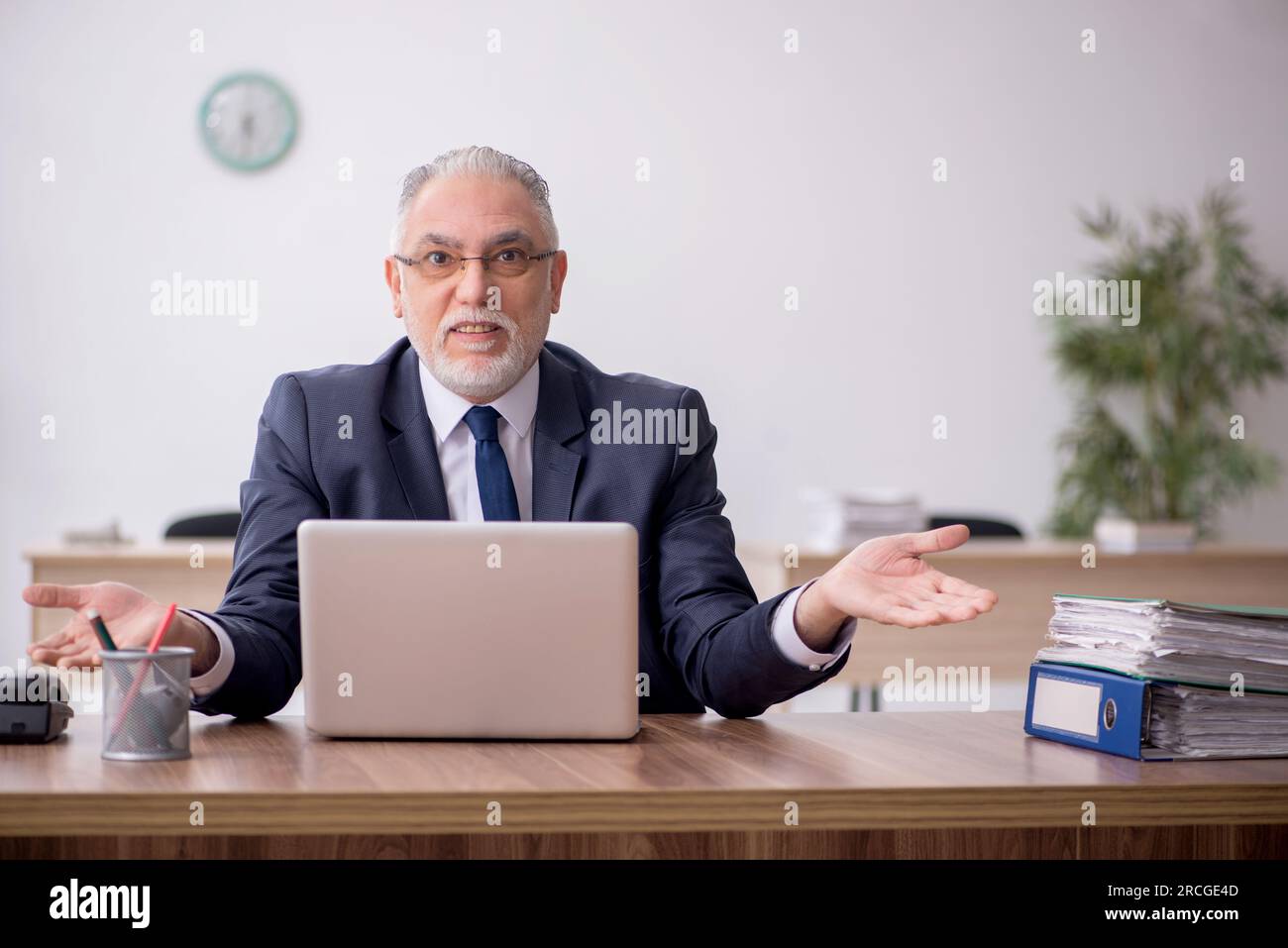 Old employee sitting at workplace Stock Photo - Alamy