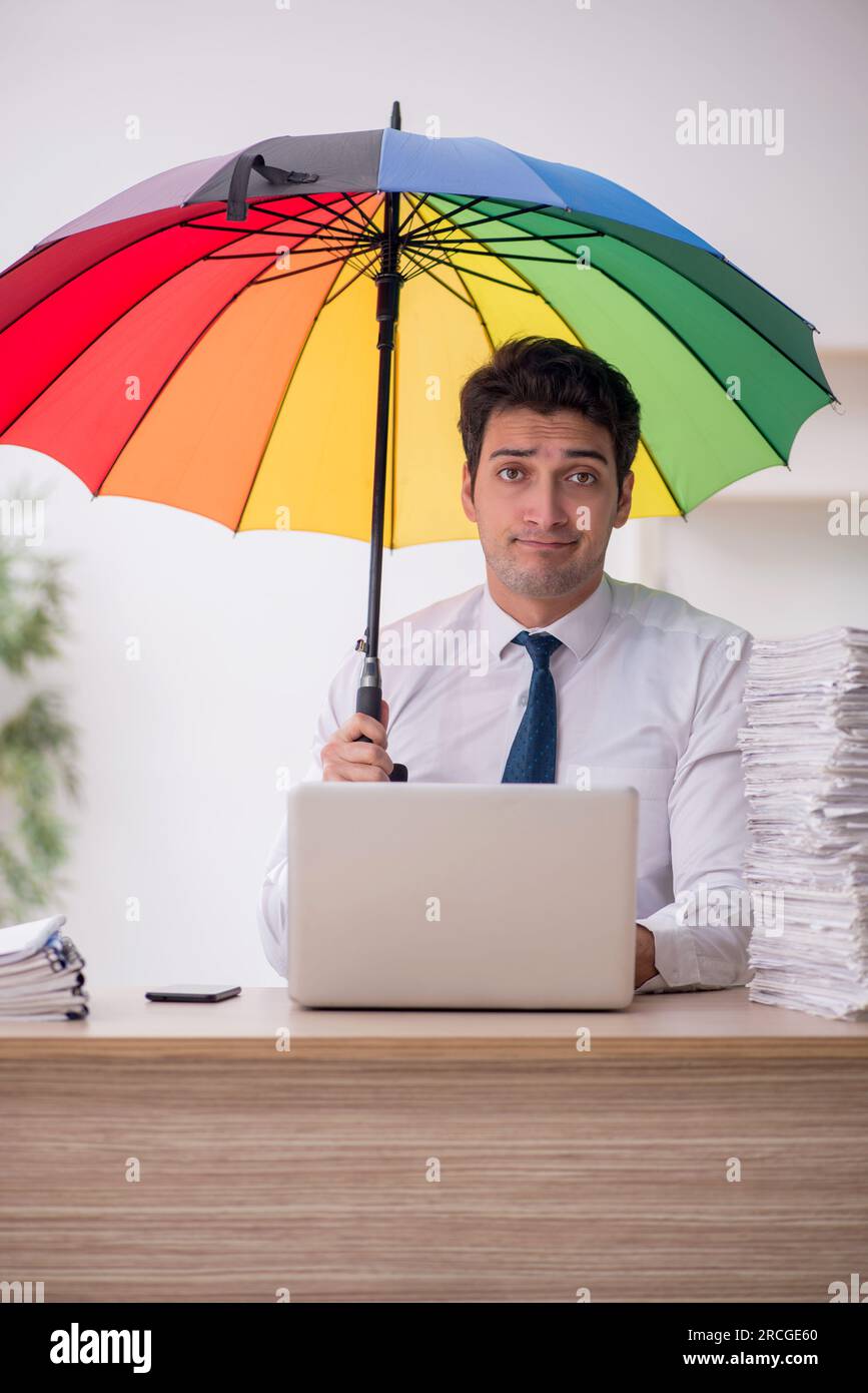 Young employee holding an umbrella at workplace Stock Photo - Alamy