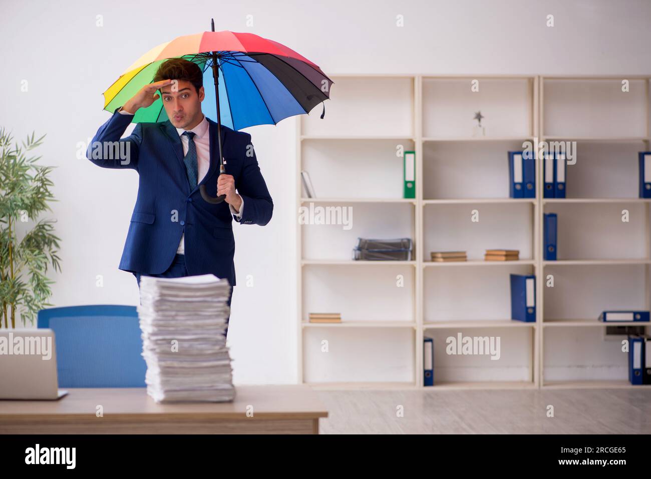 Young employee holding an umbrella at workplace Stock Photo - Alamy