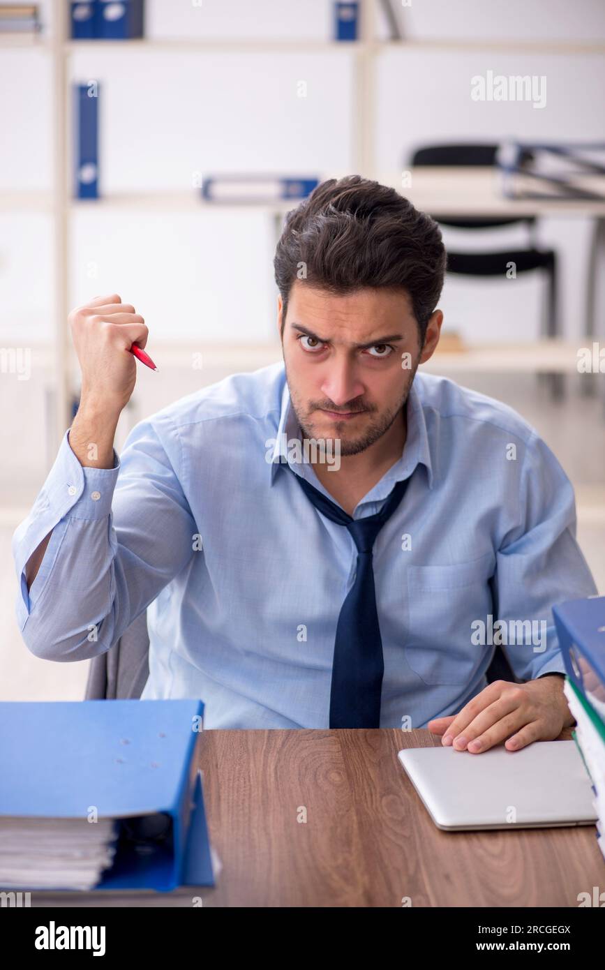 Young employee and too much work at workplace Stock Photo - Alamy