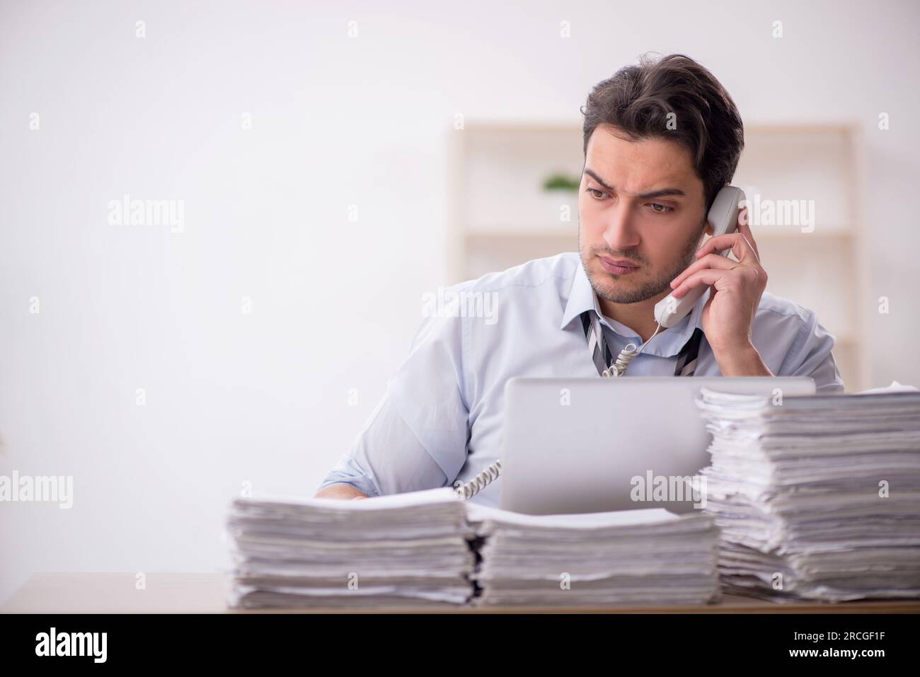 Young employee and too much work at workplace Stock Photo - Alamy