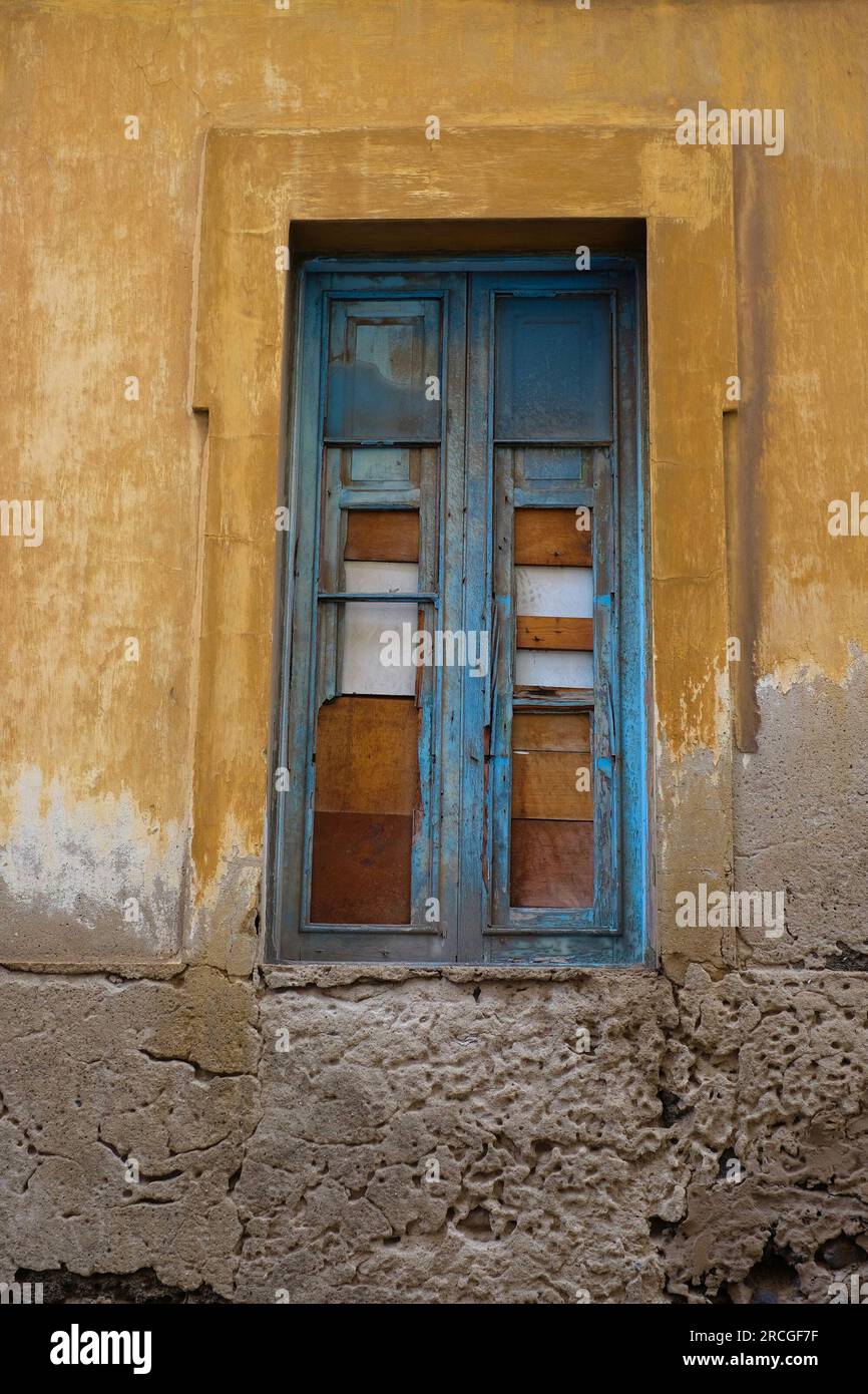 Beautiful pale blue wooden window frame in a wall of an old decaying ...