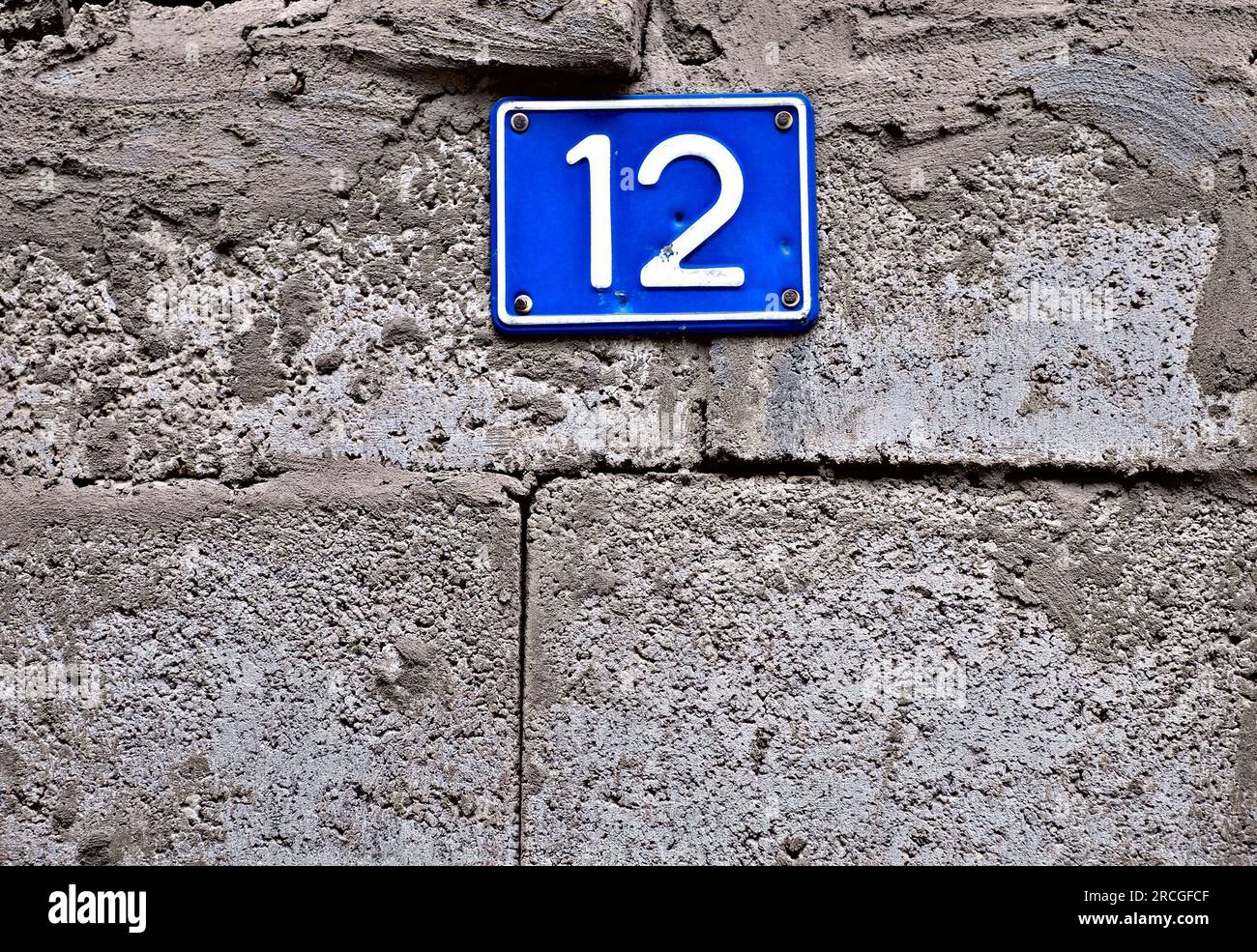 Number 12, twelve, blue plate on a gray rough concrete surface Stock ...
