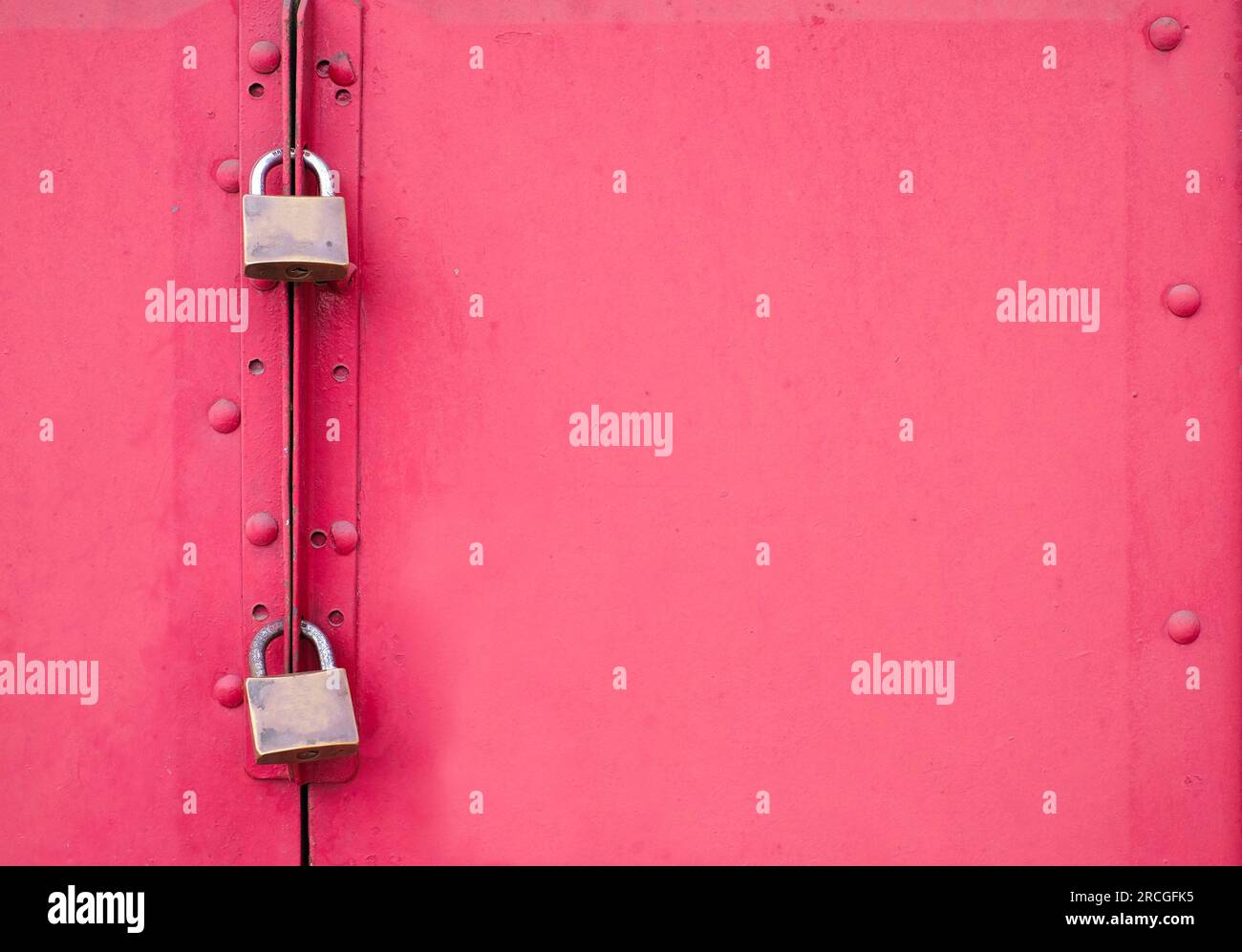 Metal red door locked with two big padlocks Stock Photo - Alamy