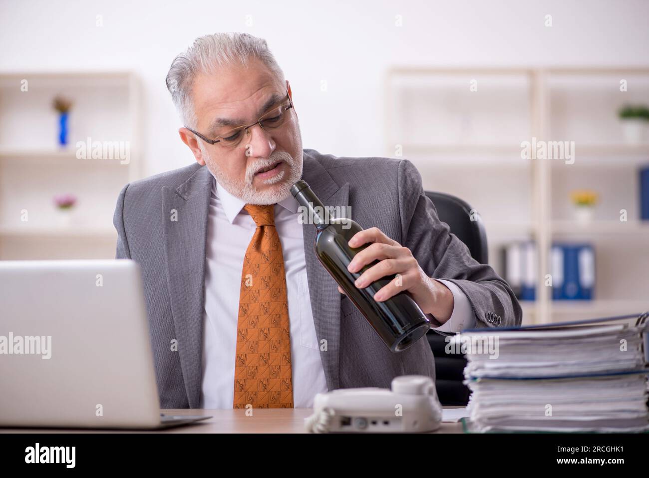 Old employee drinking alcohol at workplace Stock Photo - Alamy