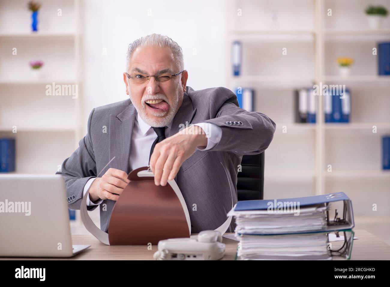 Old businessman employee eating cake at workplace Stock Photo - Alamy