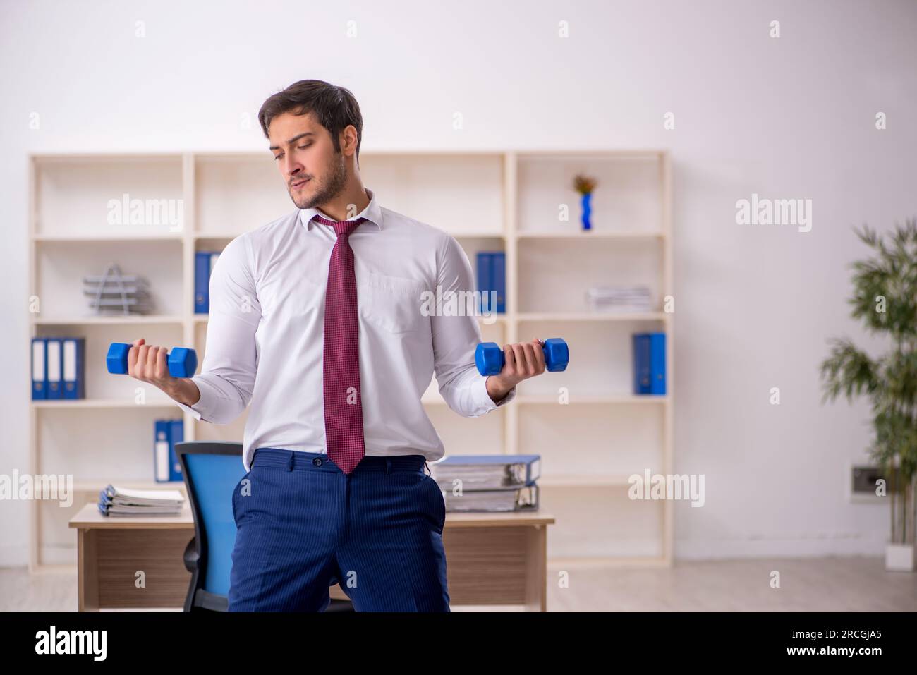 Young employee doing sport exercises during break Stock Photo - Alamy
