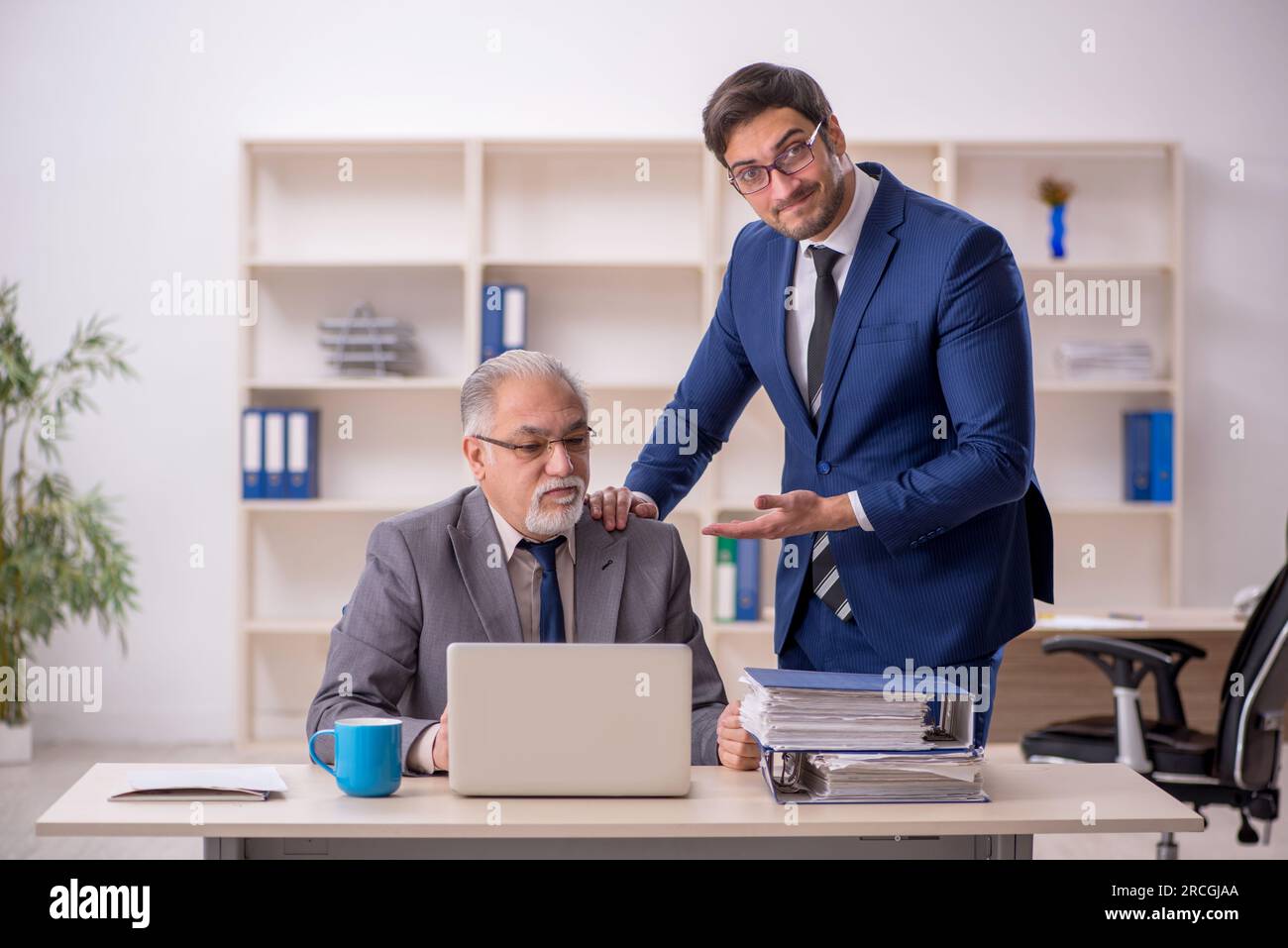 Old boss and young employee in the office Stock Photo - Alamy