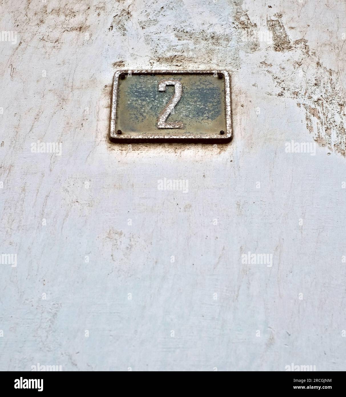 Old plate number 2, two, on a very weathered dusty wall surface, offset ...
