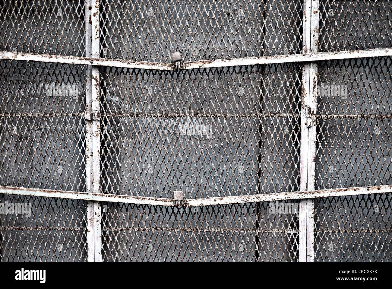 Dirty grungy wire mesh, steel bars and padlocks close access to an old ...