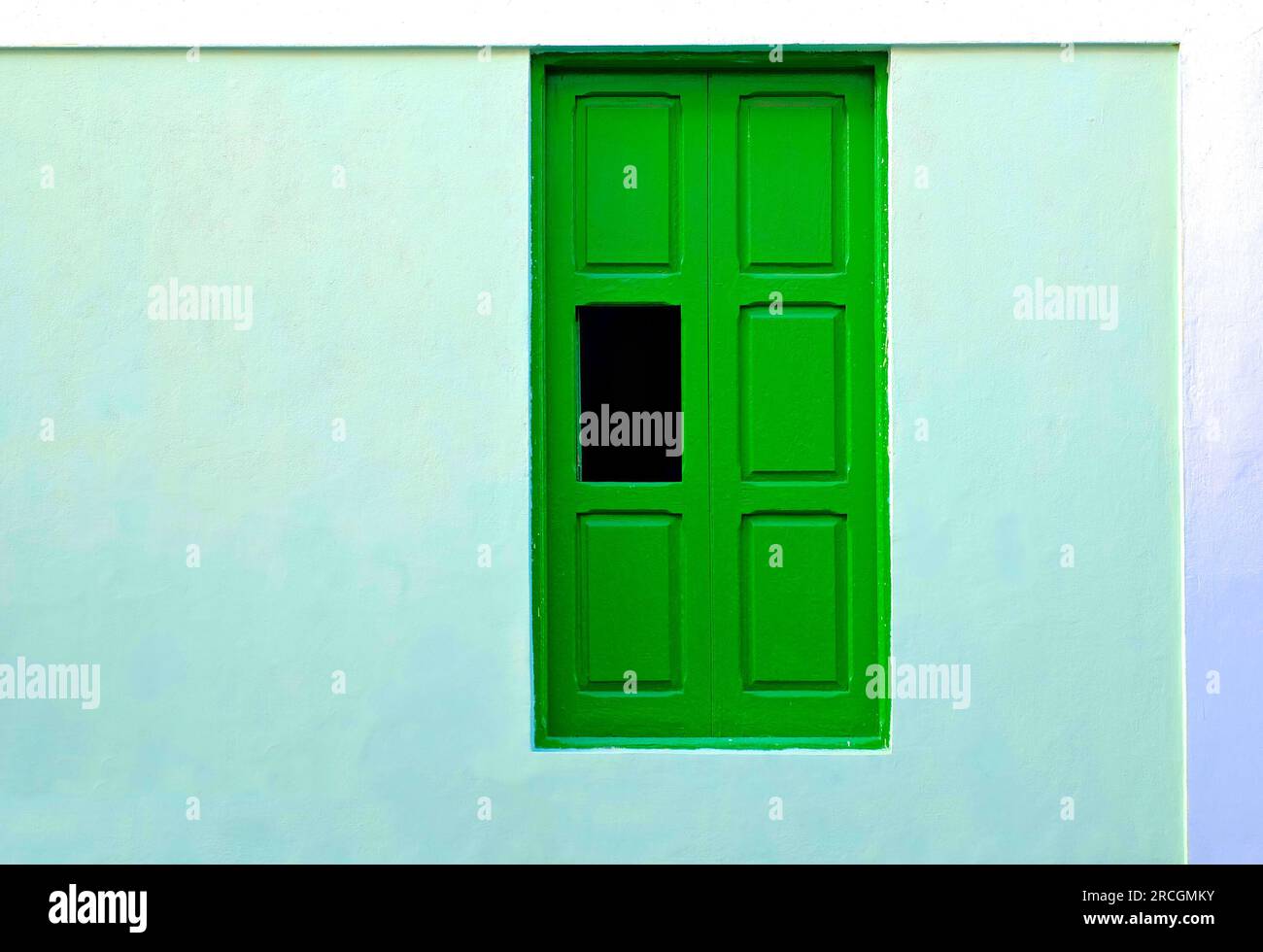 Green shutters in a pale blue wall, with one window panel open, classic ...