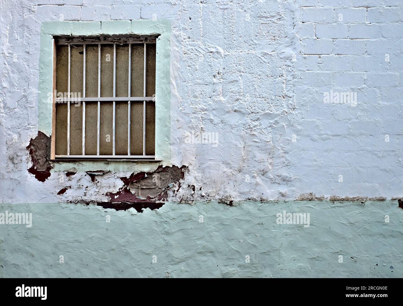 Barred window in a plain grungy wall, concept of prison and limitation ...