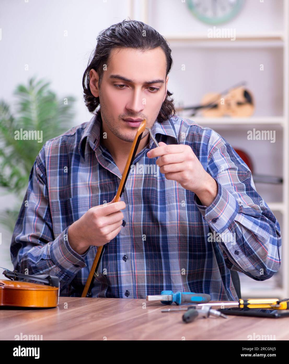 The young handsome repairman repairing violin Stock Photo - Alamy
