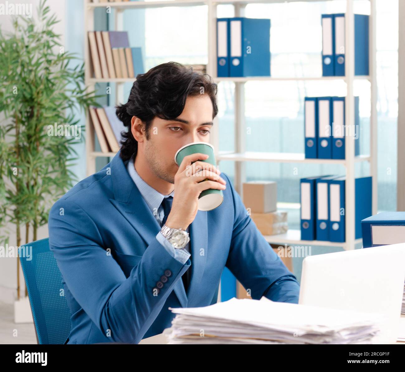 The young handsome male employee with too much work in the office Stock ...