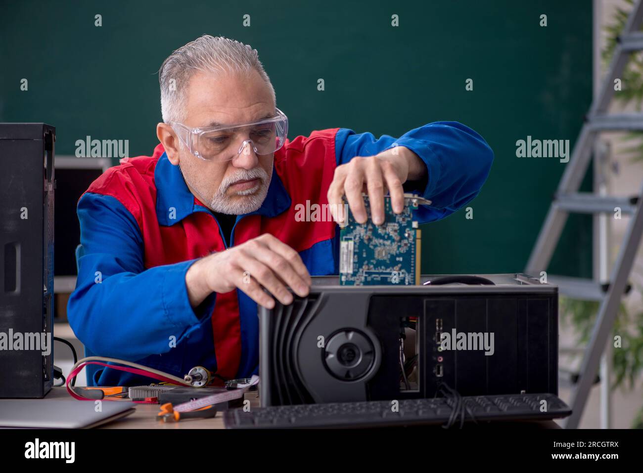Old male repairman repairing computers in the classroom Stock Photo - Alamy