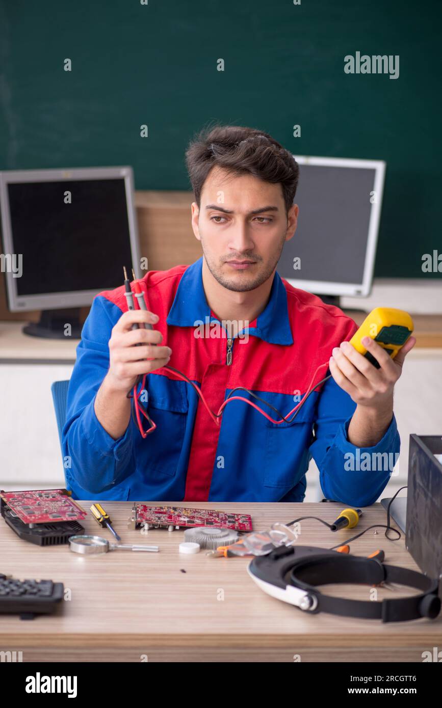 Young repairman repairing computers in the classroom Stock Photo - Alamy