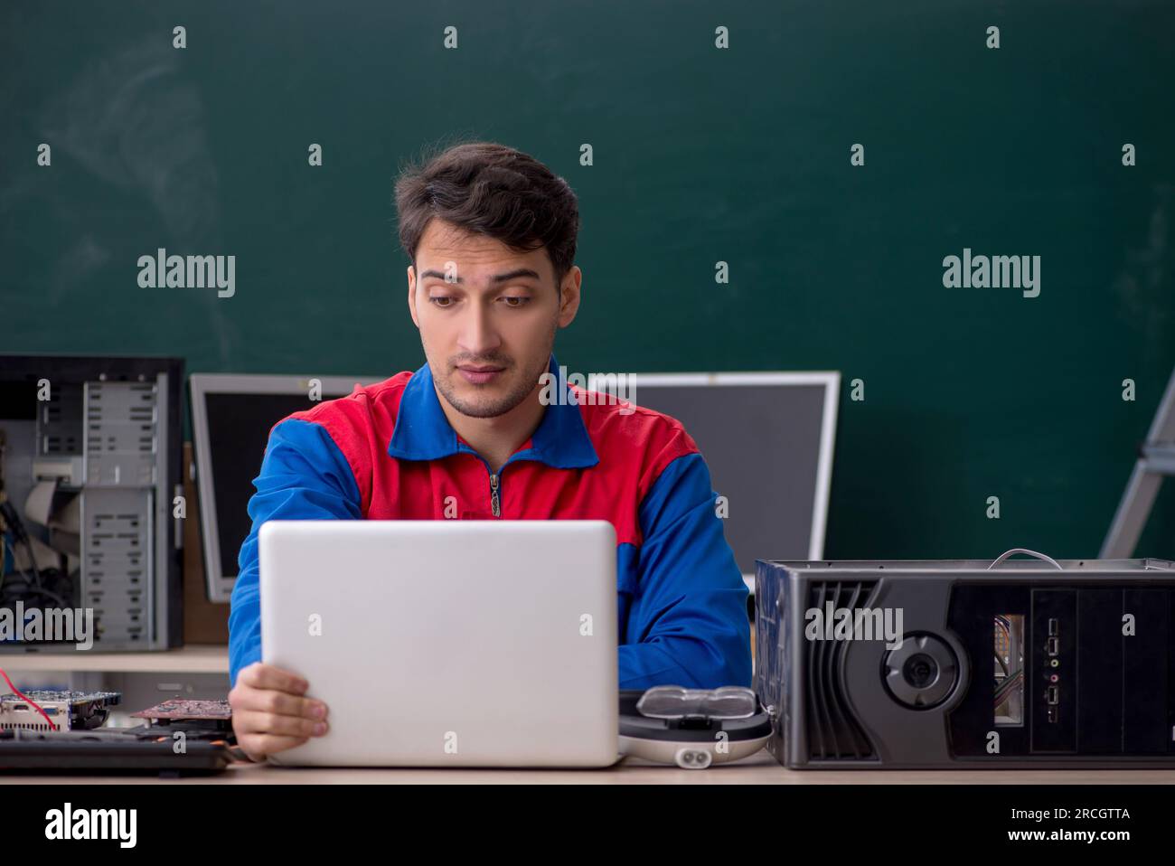Young repairman repairing computers in the classroom Stock Photo - Alamy