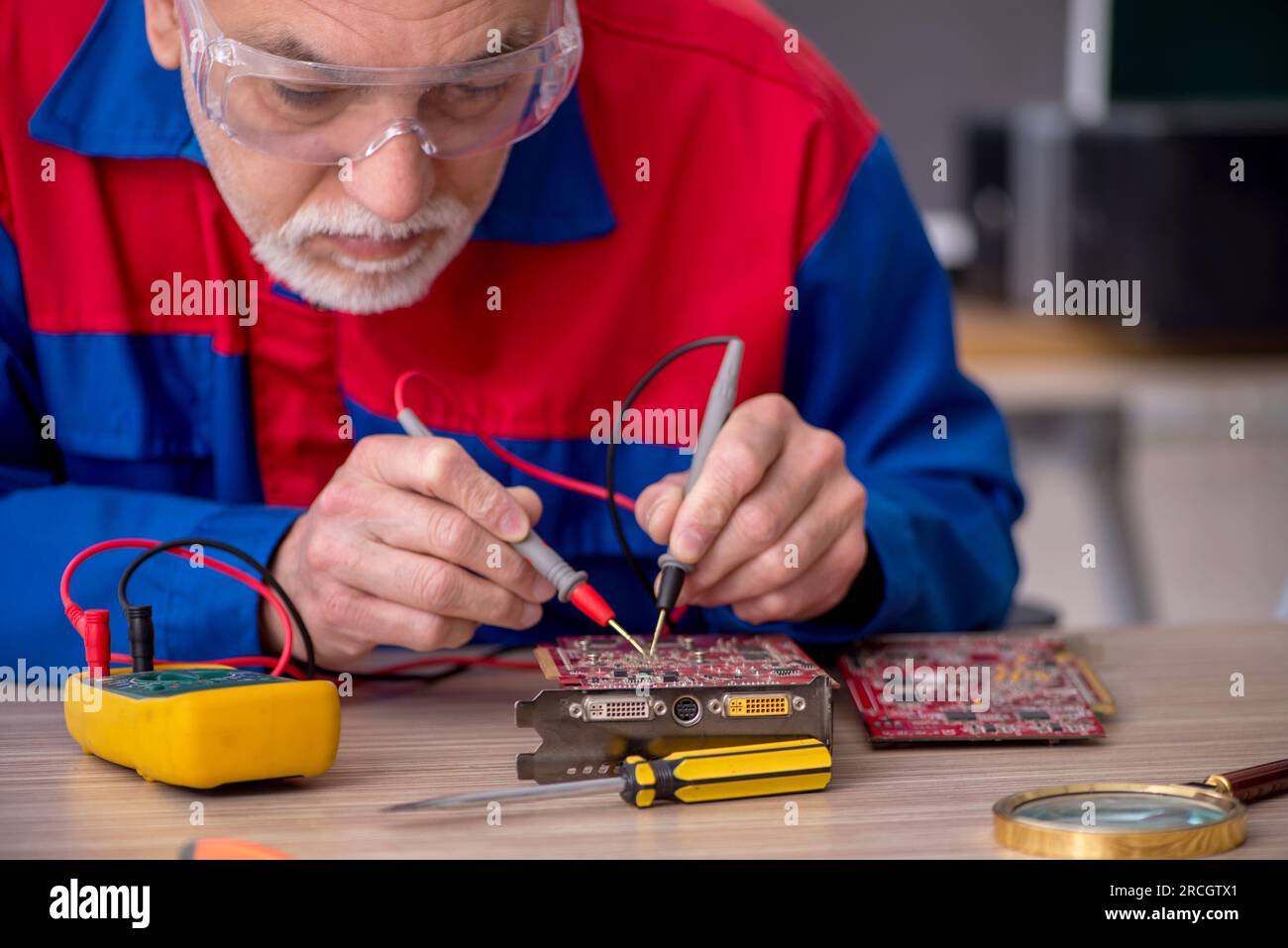 Old male repairman repairing computers in the classroom Stock Photo - Alamy