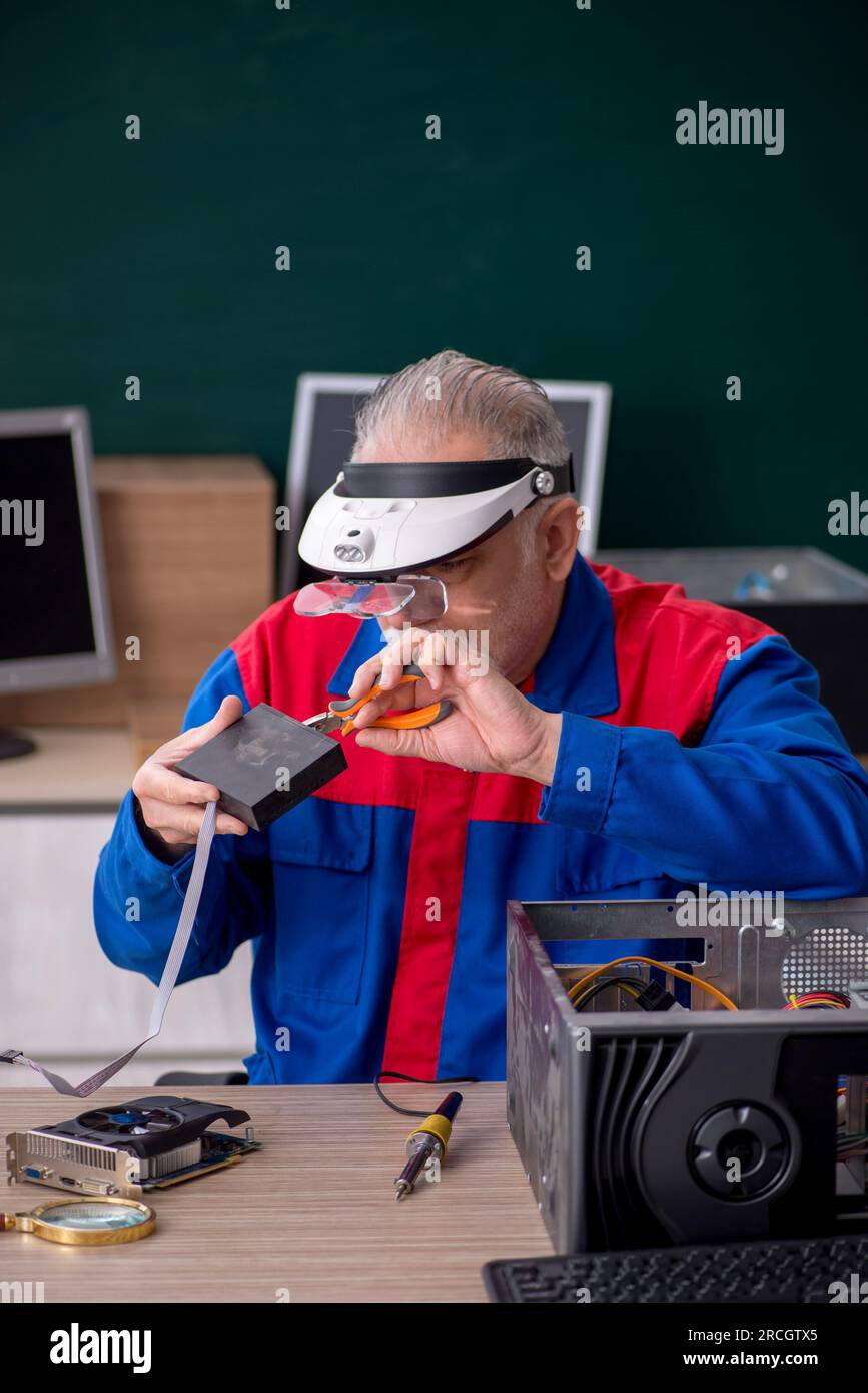 Old male repairman repairing computers in the classroom Stock Photo - Alamy