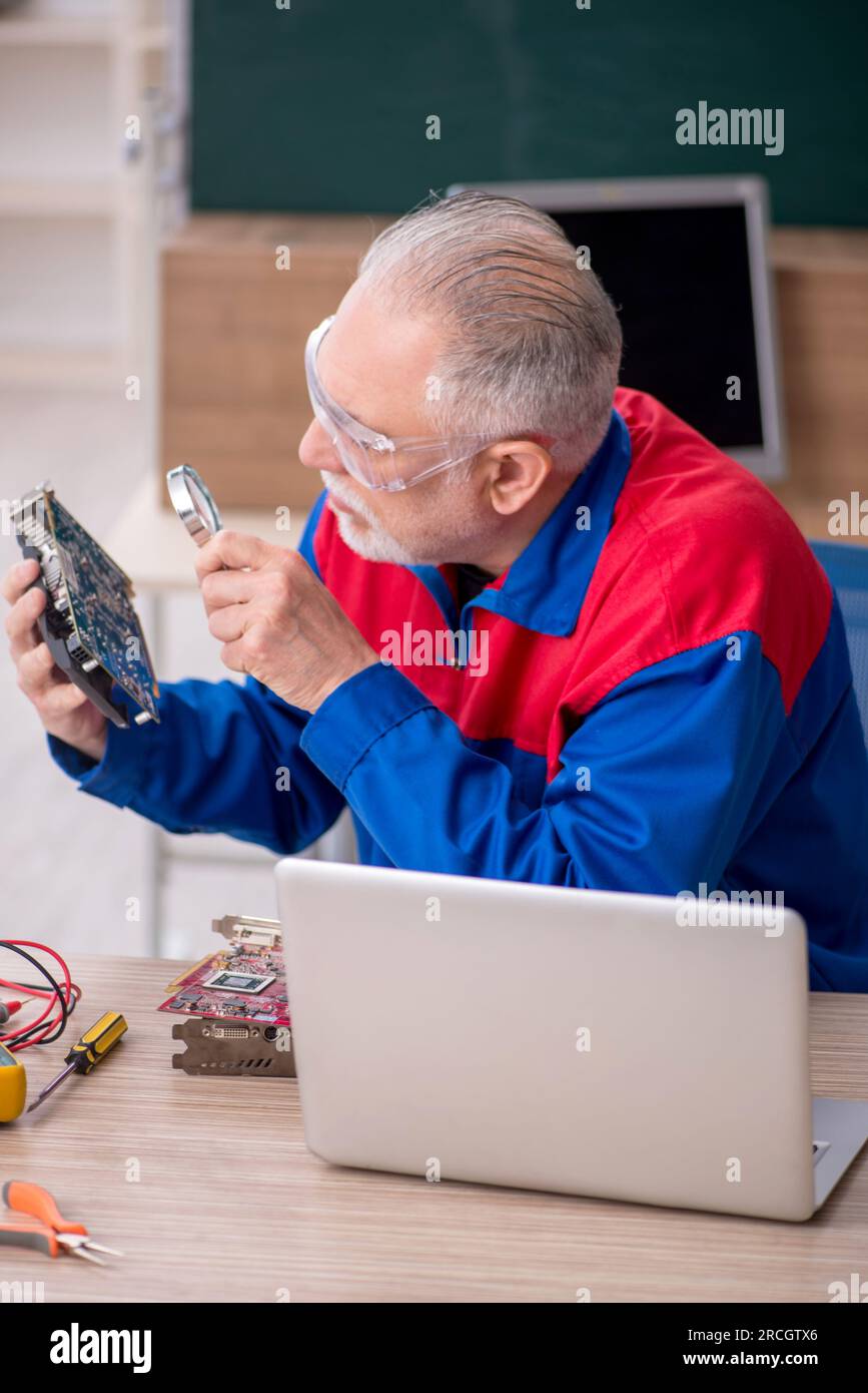 Old male repairman repairing computers in the classroom Stock Photo - Alamy
