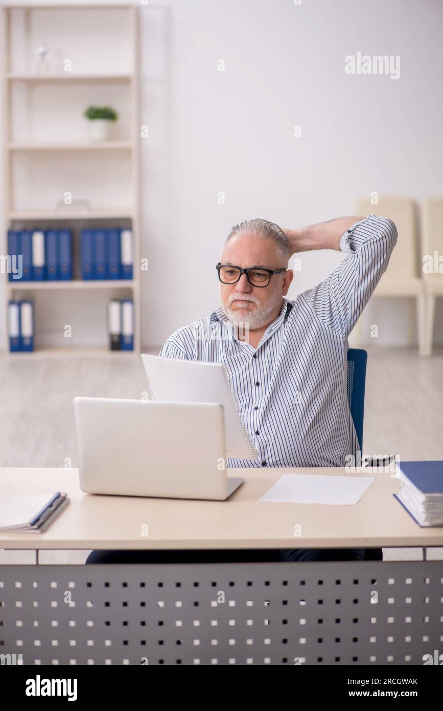 Old employee working at workplace Stock Photo - Alamy