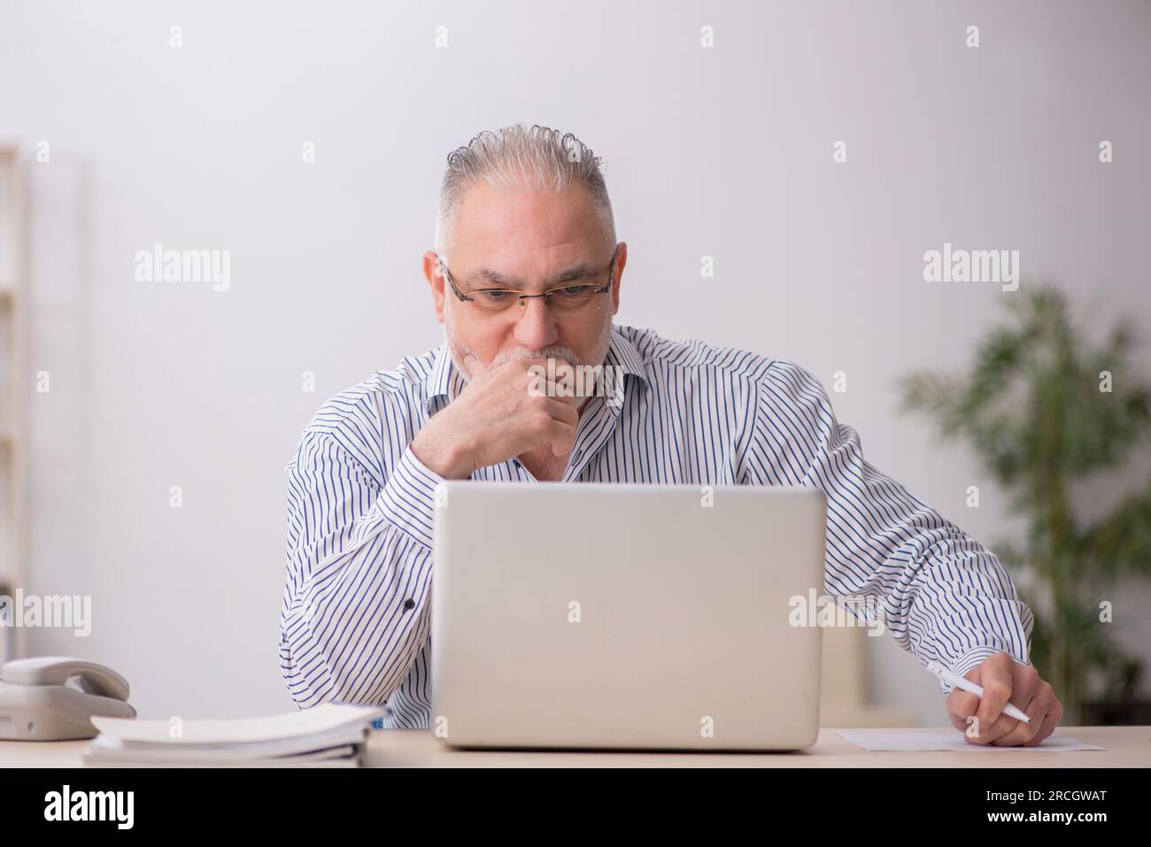 Old employee working at workplace Stock Photo - Alamy
