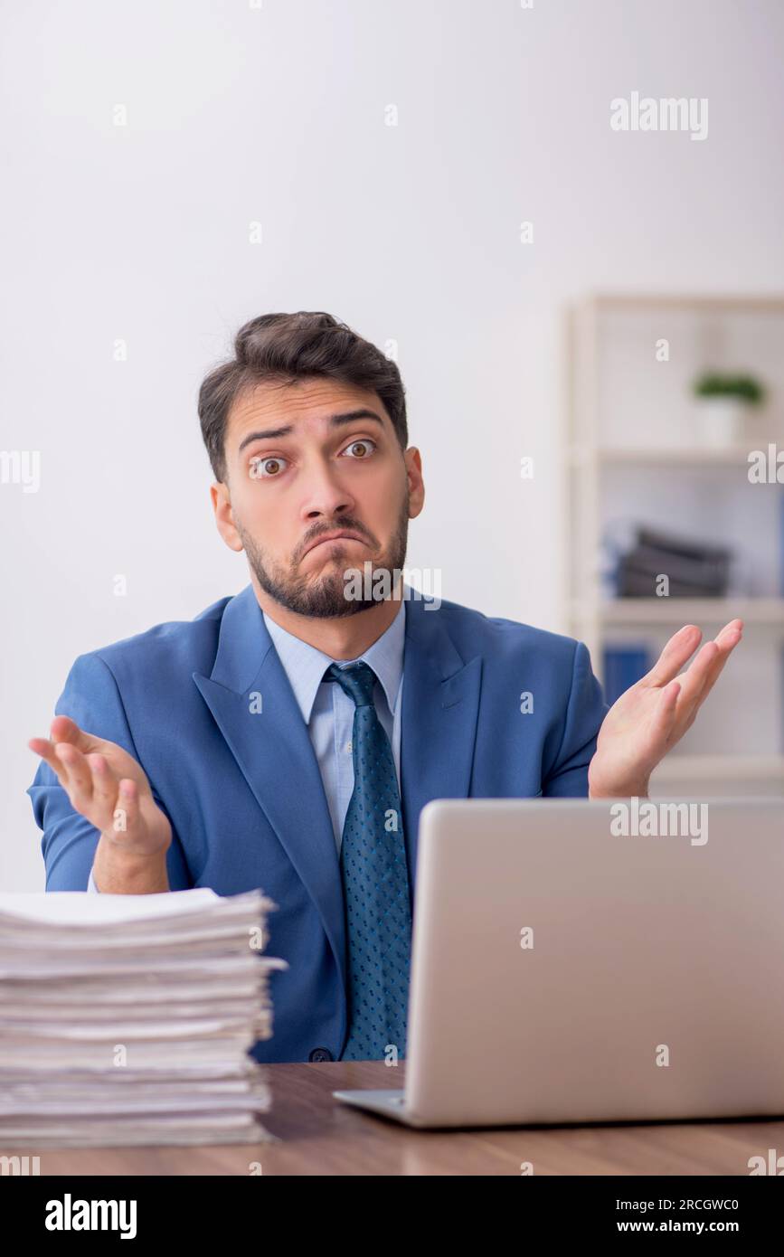Young employee and too much work at workplace Stock Photo - Alamy