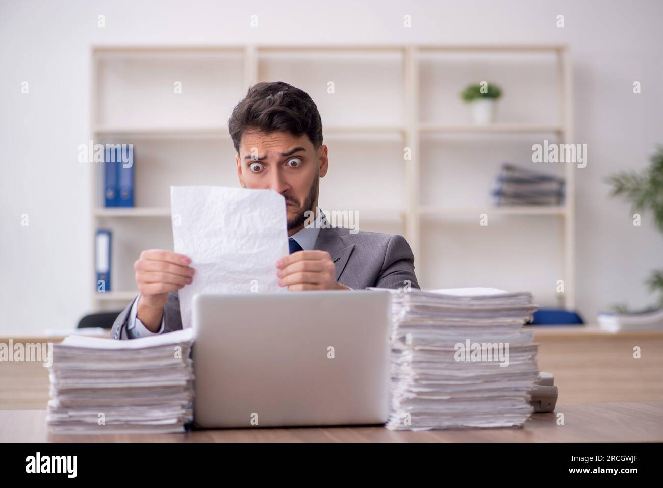 Young employee and too much work at workplace Stock Photo - Alamy