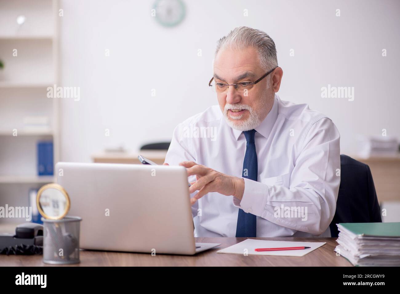 Old employee sitting at workplace Stock Photo - Alamy