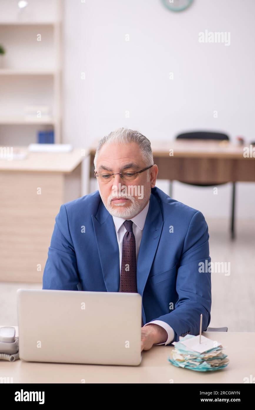 Old employee sitting at workplace Stock Photo - Alamy