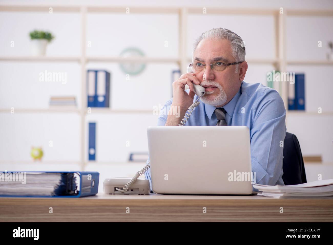 Old employee speaking by phone at workplace Stock Photo - Alamy