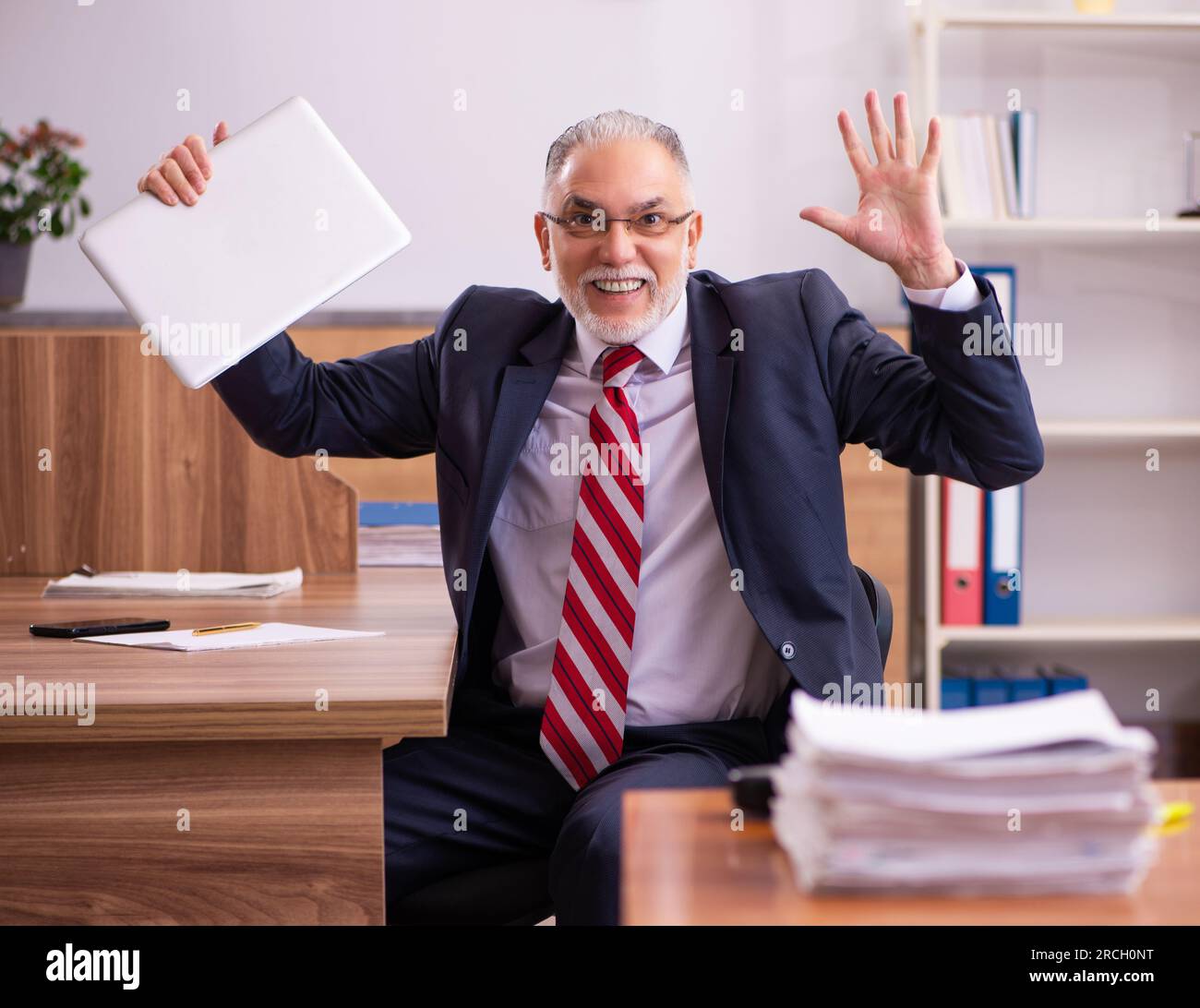 Old male employee sitting at workplace Stock Photo - Alamy