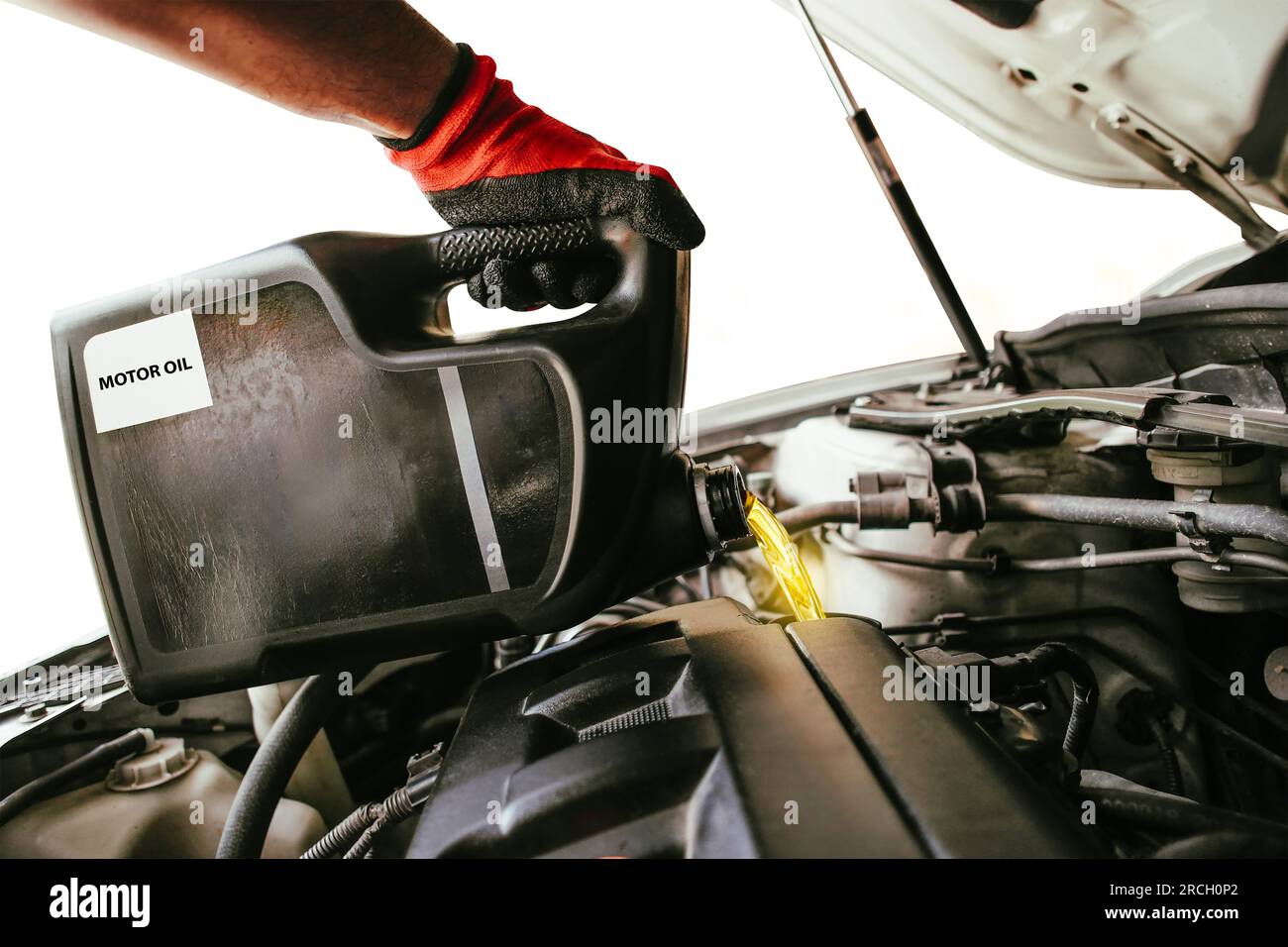 Car mechanic pouring engine oil into engine, changing engine oil, car ...