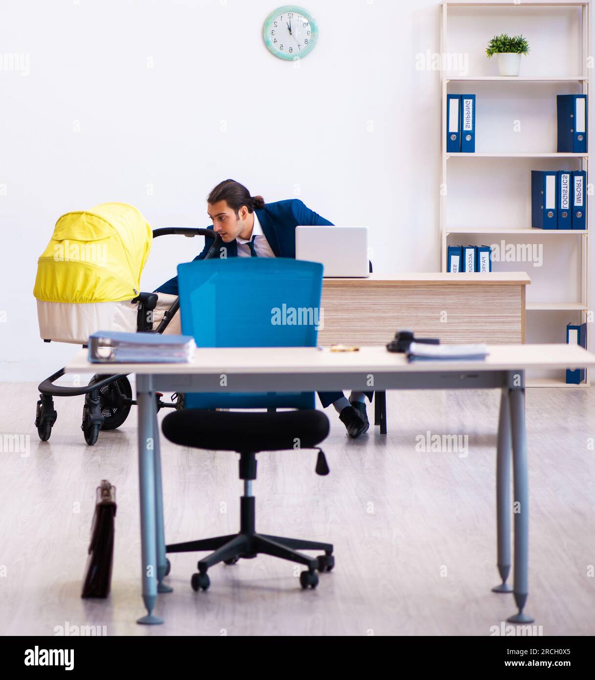 Young employee looking after kid at workplace Stock Photo - Alamy
