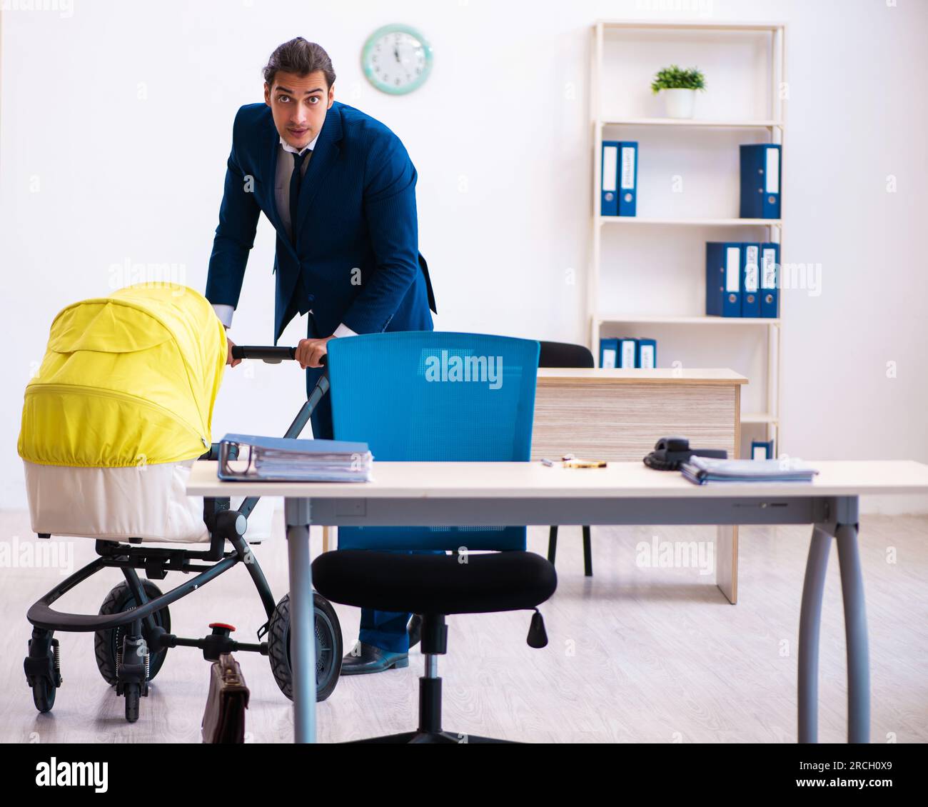 Young employee looking after kid at workplace Stock Photo - Alamy