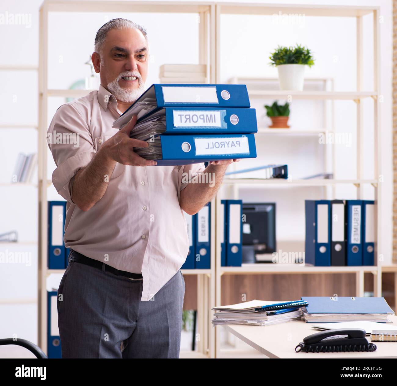 Senior male employee doing physical exercises at workplace Stock Photo ...