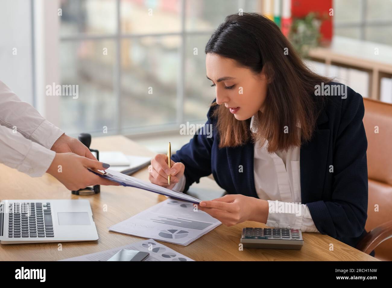 Female accountant working with colleague at table in office Stock Photo ...