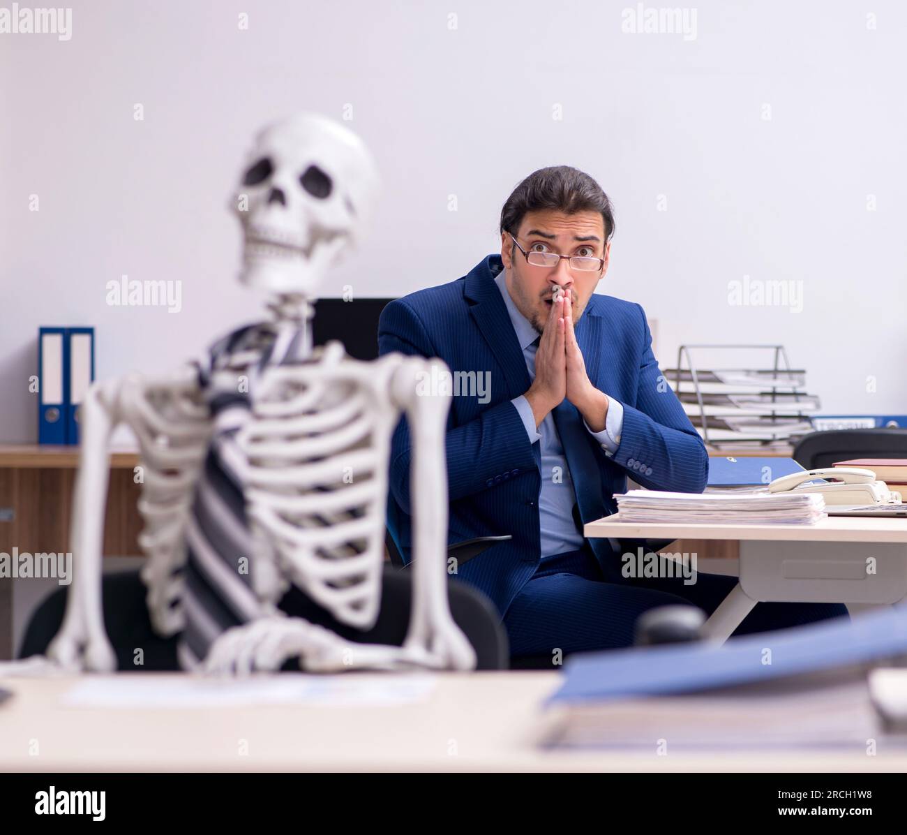 Young employee with skeletons in the office Stock Photo - Alamy