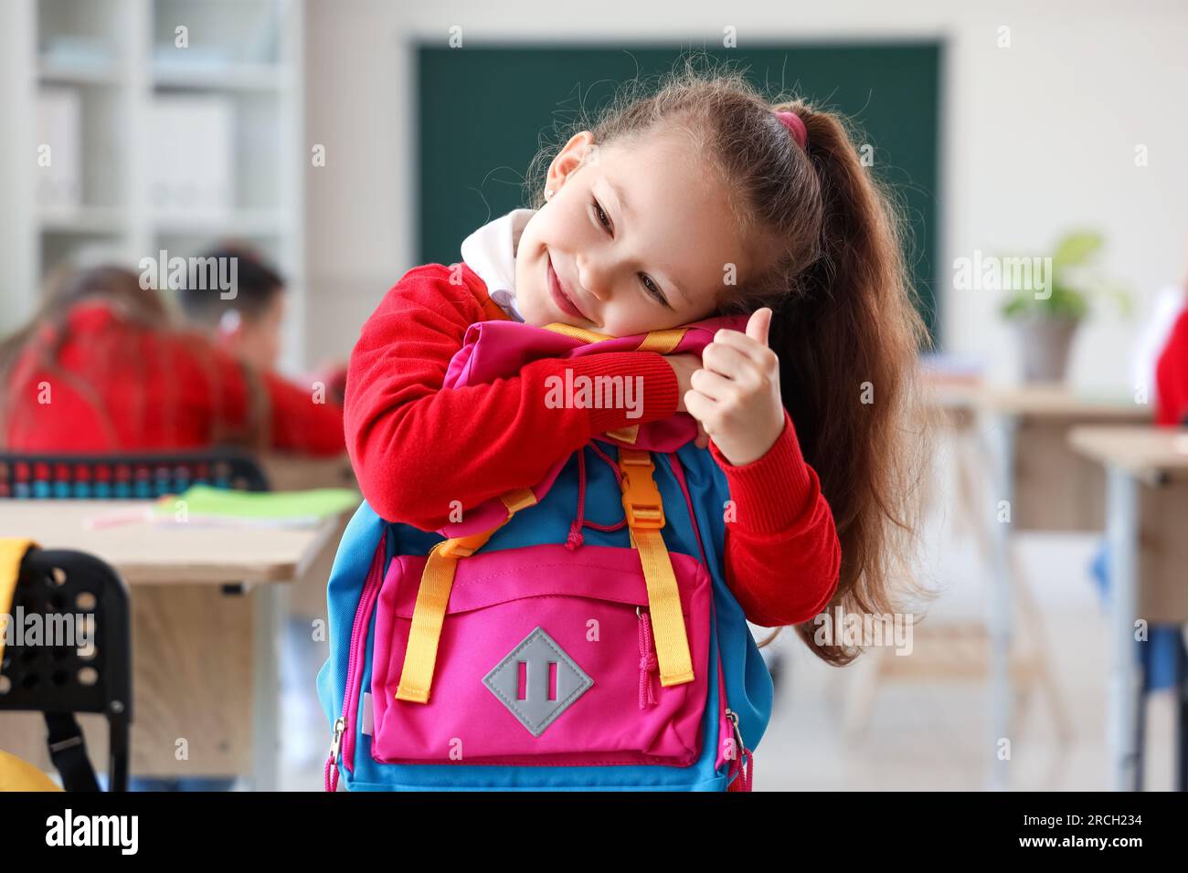 Cute little schoolgirl with backpack in classroom Stock Photo - Alamy