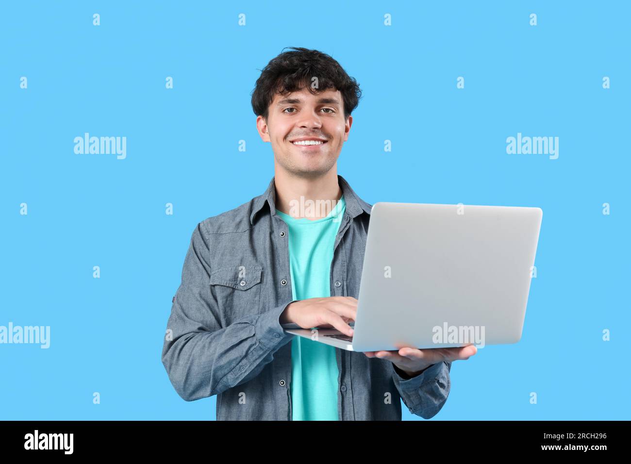 Male programmer working with laptop on blue background Stock Photo - Alamy
