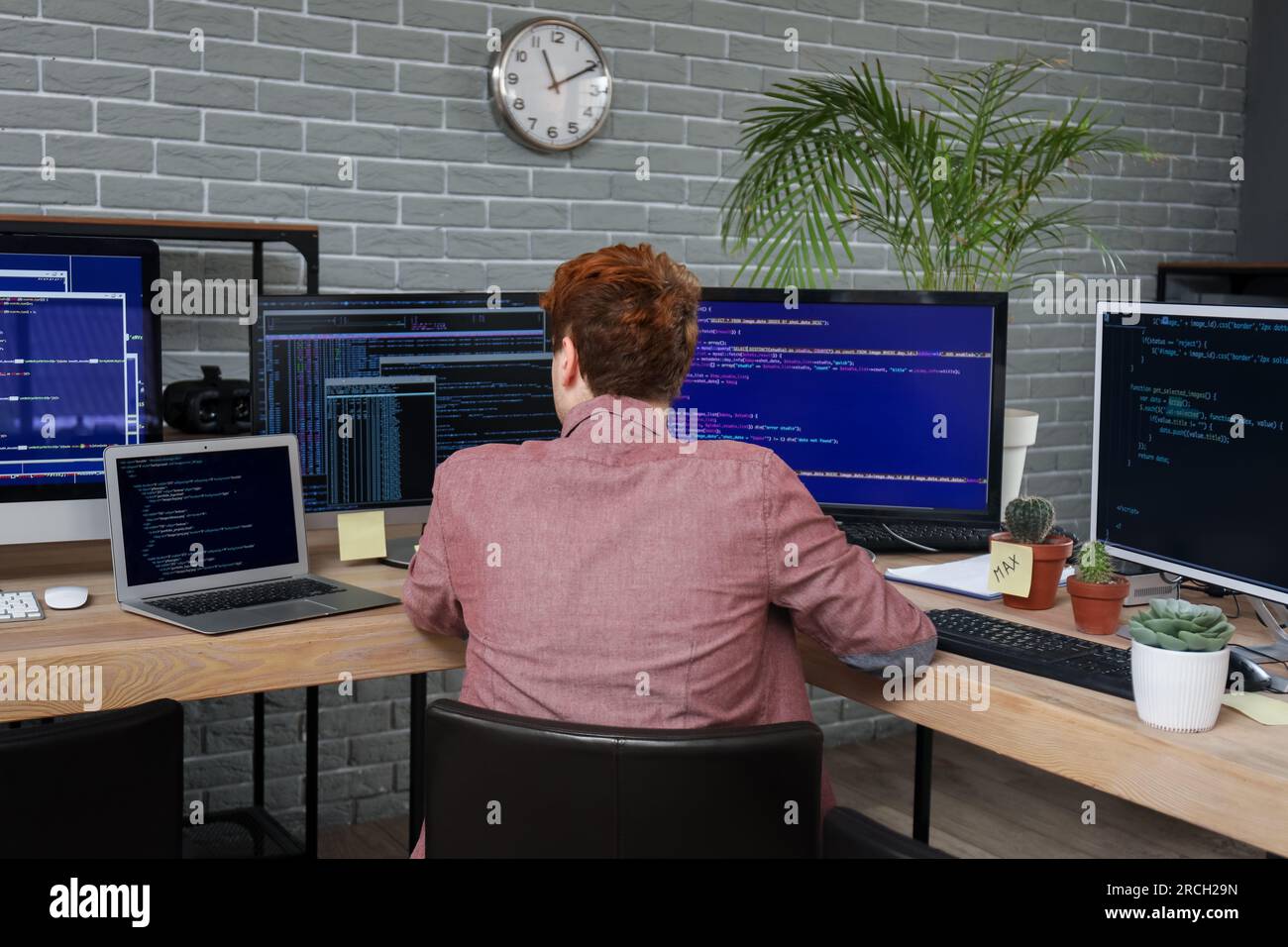Male programmer working with computer at table in office, back view ...