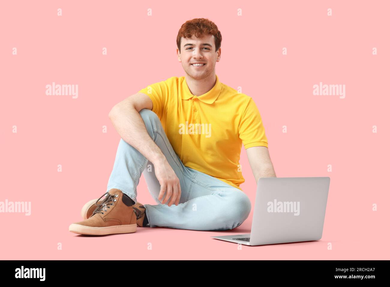 Male programmer working with laptop on pink background Stock Photo - Alamy